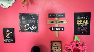 Paredes com diversos letreiros motivacionais e uma máquina de café sobre um balcão.