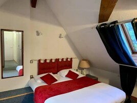 Quarto com cama, espelho, mesa de cabeceira e janela com cortinas.