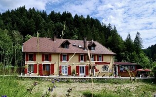 Uma casa de dois andares com telhado de telhas vermelhas, várias chaminés e alicerce de pedra.