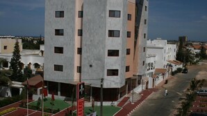 Um edifício de vários andares com design moderno, apresentando um pátio central com área verde e caminhos vermelhos.