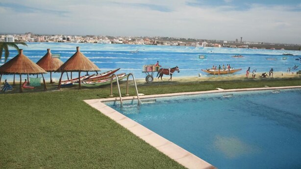 Piscina com vista para o mar e paisagem urbana ao fundo.