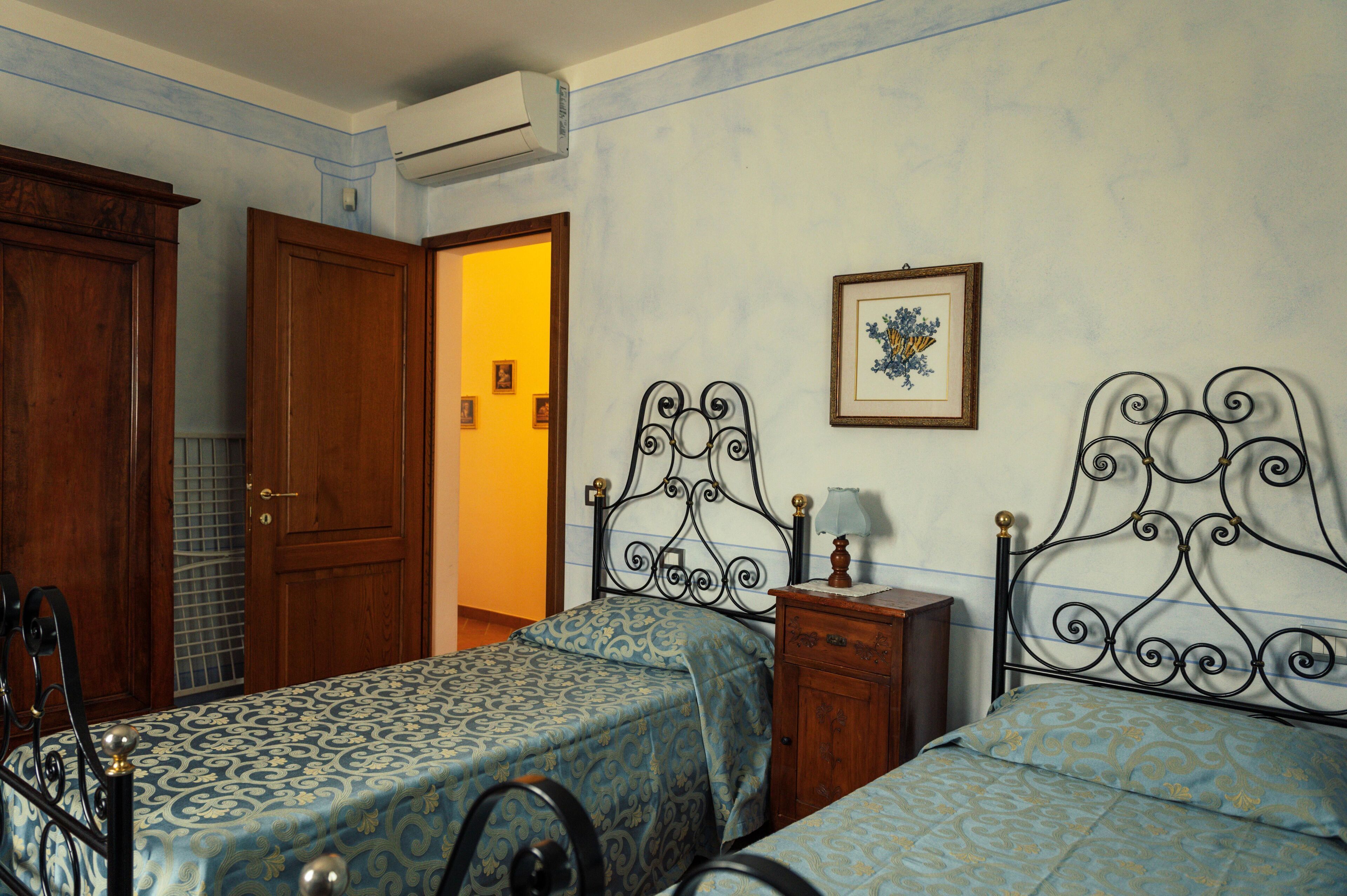 Quarto com duas camas, guarda-roupa de madeira e um quadro na parede.