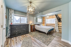 Quarto com cama, penteadeira e janelas.