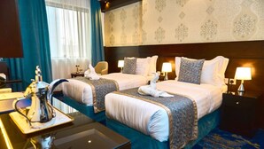 Quarto de hotel com duas camas, uma escrivaninha com abajur e vista para o exterior.