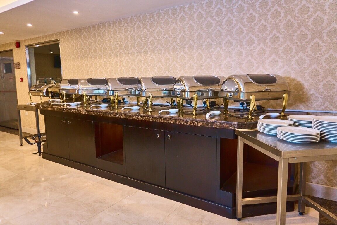 Uma mesa de buffet com várias estações de serviço, bancada de mármore e mesa de metal com pratos.