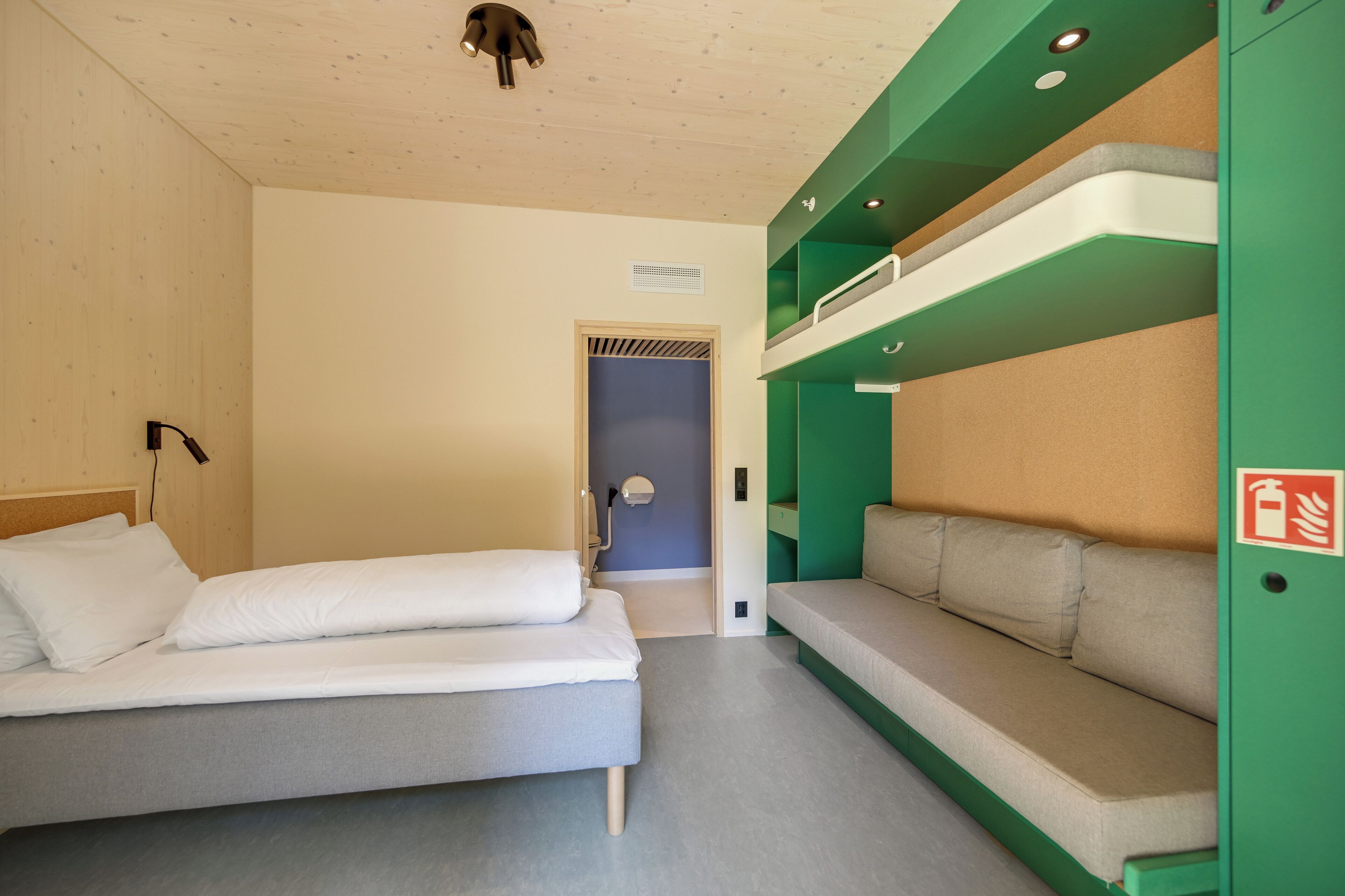 Um quarto com cama, sofá, beliche e porta que dá para outro cômodo.