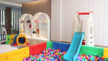 Uma área de recreação infantil com piscina de bolinhas, escorregadores e prateleiras de armazenamento.