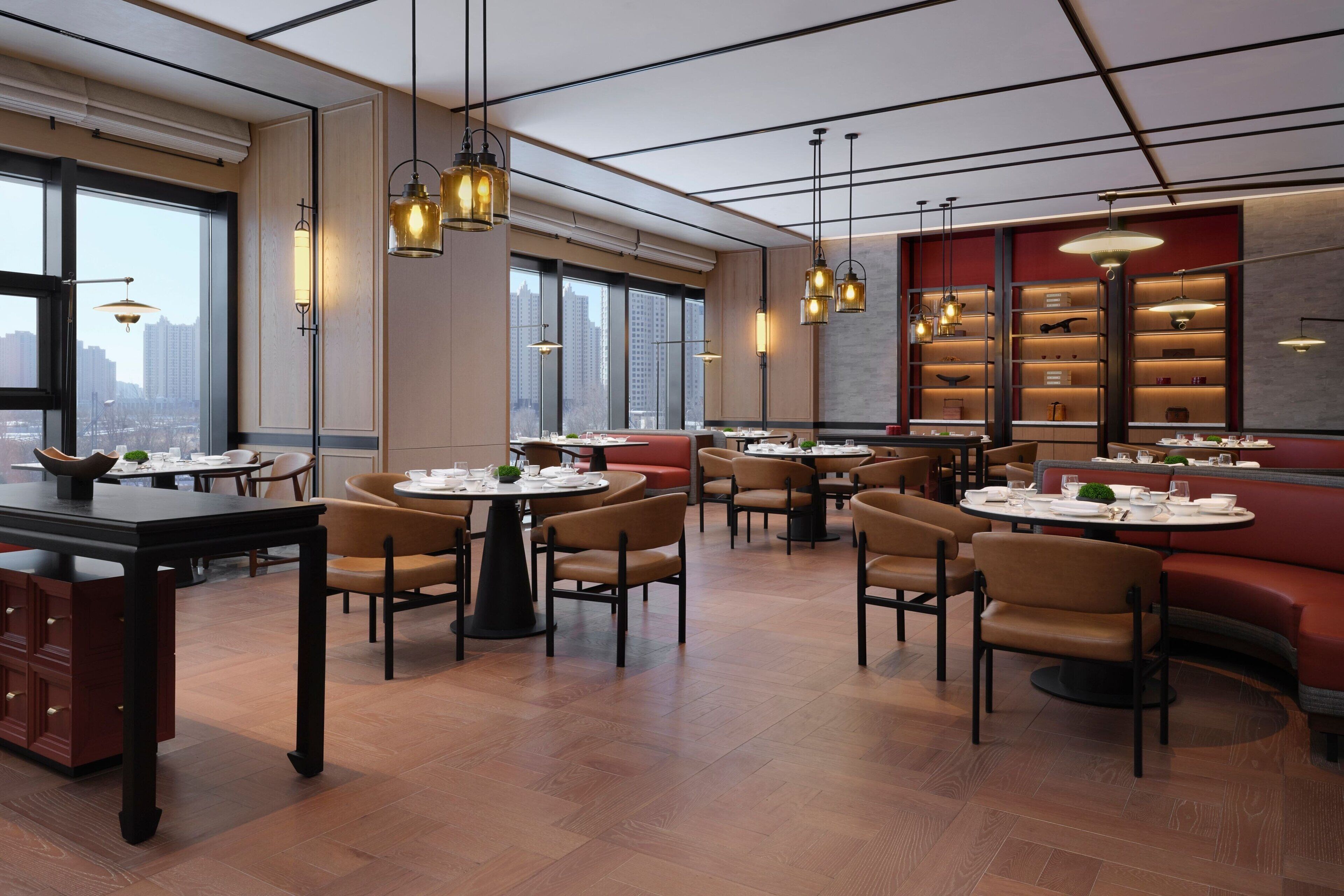 Uma sala de jantar moderna com mesas redondas, assentos em couro e iluminação pendente.