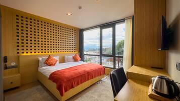 Quarto de hotel moderno com uma cama grande, uma escrivaninha, um chuveiro e uma televisão.