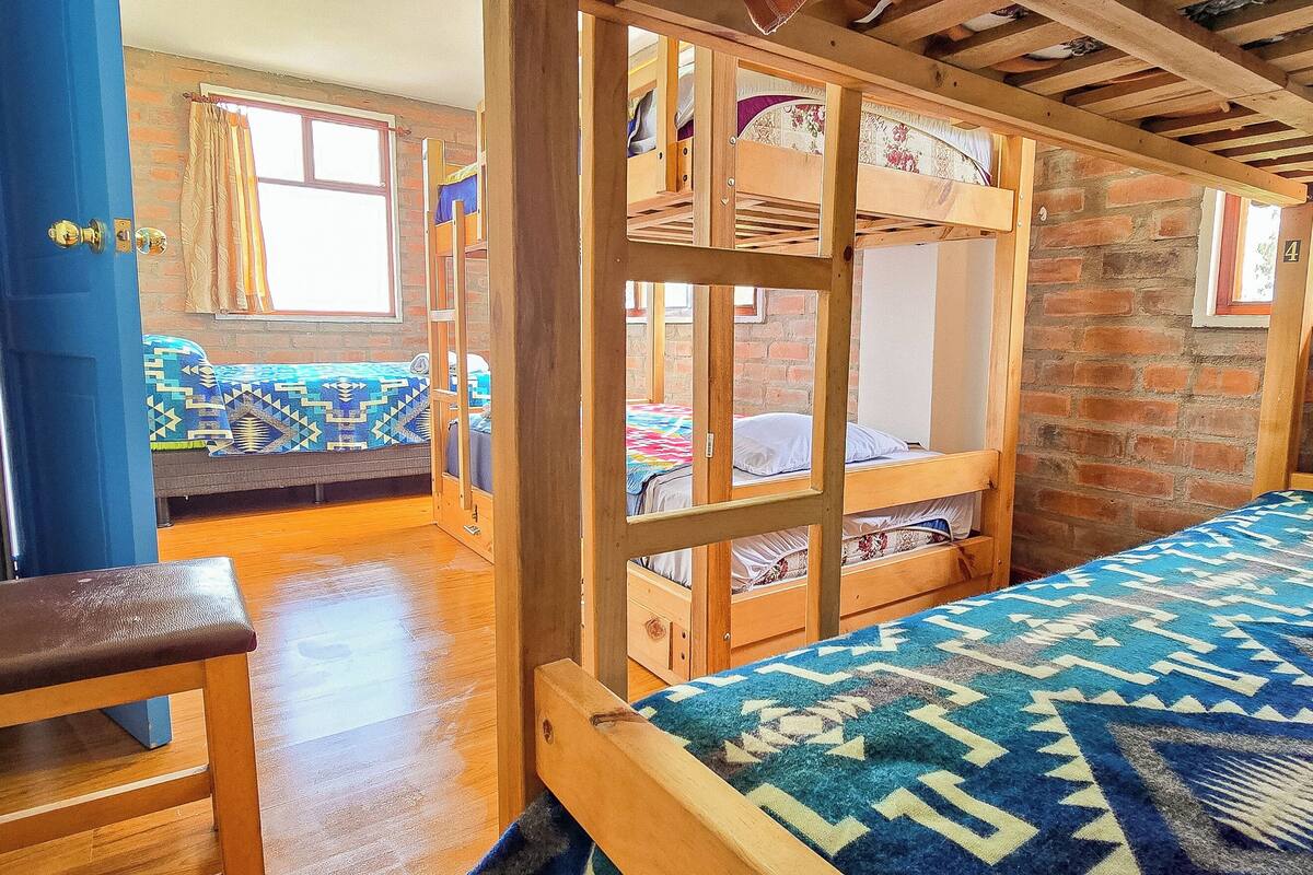 Quarto com uma cama de beliche, uma cadeira de madeira e um edredom estampado.