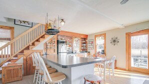 Cozinha ampla com uma ilha grande, escada de madeira e vista para o exterior.