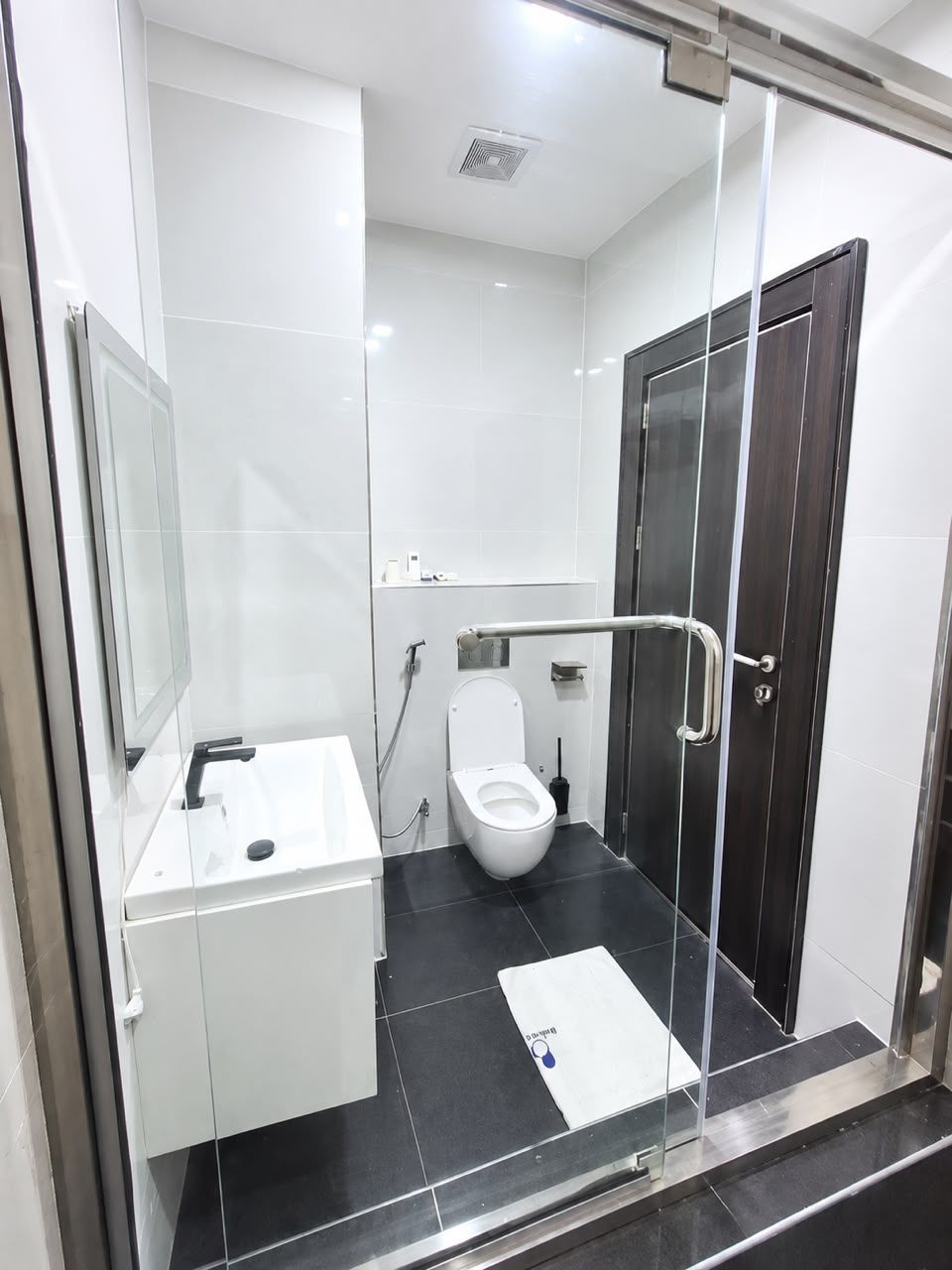 Casa de banho moderna com cabine de duche em vidro, lavatório branco e sanita.