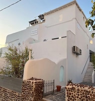 Um edifício branco com uma placa que diz "The Muses of Santorini".