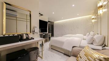 Quarto de hotel moderno com uma cama grande, escrivaninha com espelho, televisão de tela plana e minibar.