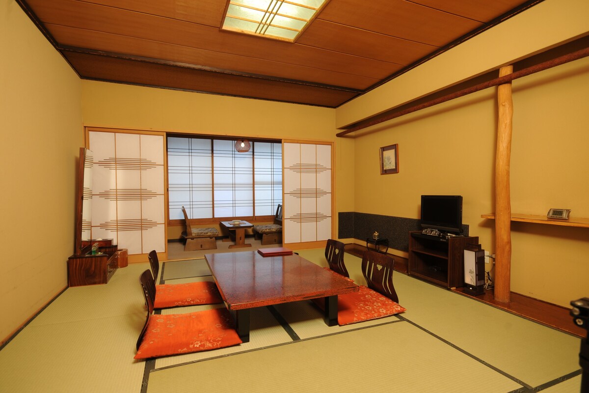 Um quarto japonês tradicional com tatames, uma mesa baixa e portas deslizantes.