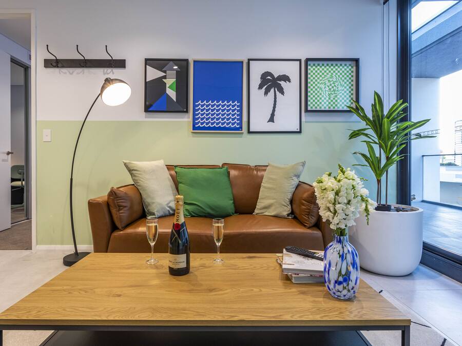 Uma sala de estar moderna com um sofá de couro marrom, uma mesa de centro de madeira e uma grande planta em vaso.
