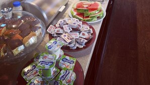 Buffet com diversos alimentos, incluindo frutas, carnes e produtos lácteos.