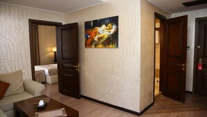 Quarto de hotel com cama, sofá, mesa de centro e um quadro na parede.
