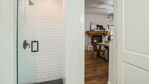 Casa de banho moderna com azulejos brancos tipo metrô e cabine de chuveiro em vidro.