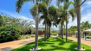 Um jardim bem cuidado com palmeiras, área de piscina e um caminho.