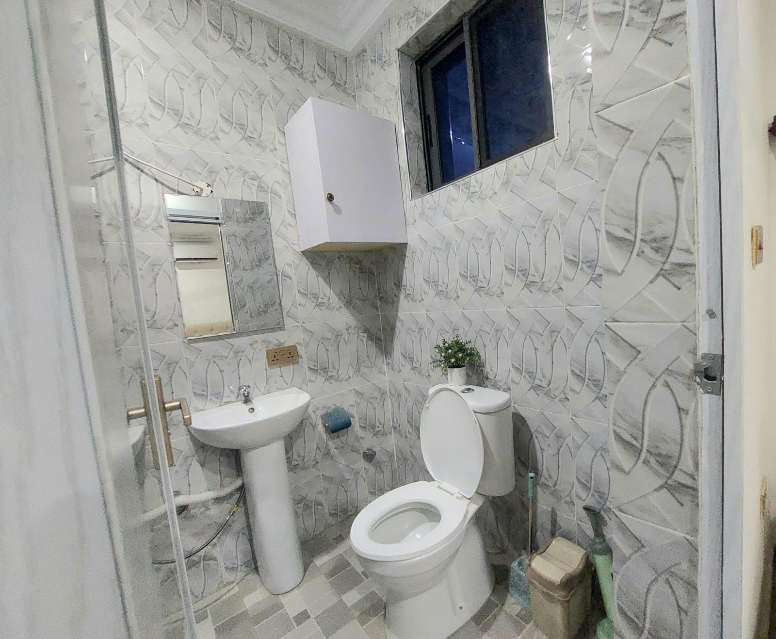 Casa de banho com lavatório assentado, sanita e pequena janela.