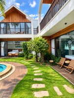 Um edifício moderno de dois andares com piscina, área de estar ao ar livre e um jardim bem cuidado.