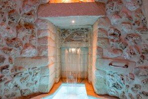 Quarto com paredes de pedra, um elemento de água e um puxador de metal na parede.