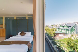 Quarto de hotel com uma cama grande, vista da cidade e uma varanda.