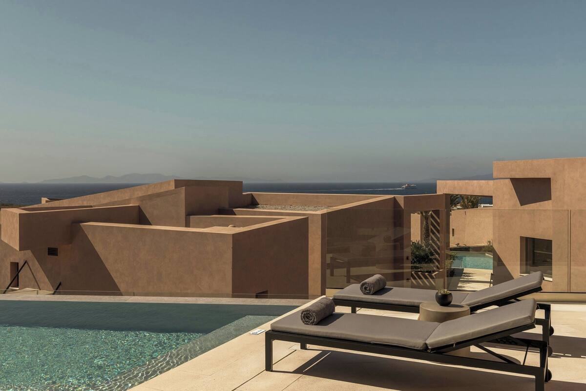Uma área de piscina moderna com espreguiçadeiras e vista clara para o oceano.