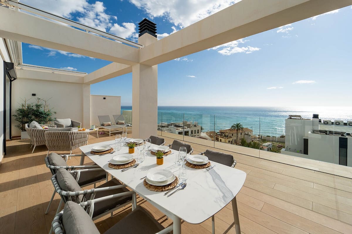 Uma área de refeições com uma mesa posta para quatro, com vista para o litoral.