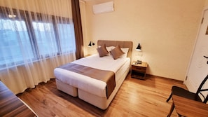 Uma cama bem arrumada com cabeceira, uma mesa de cabeceira com abajur e uma cadeira.