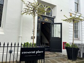 Entrada de um edifício com uma placa indicando 'Crescent Place' e uma escadaria que leva ao interior.