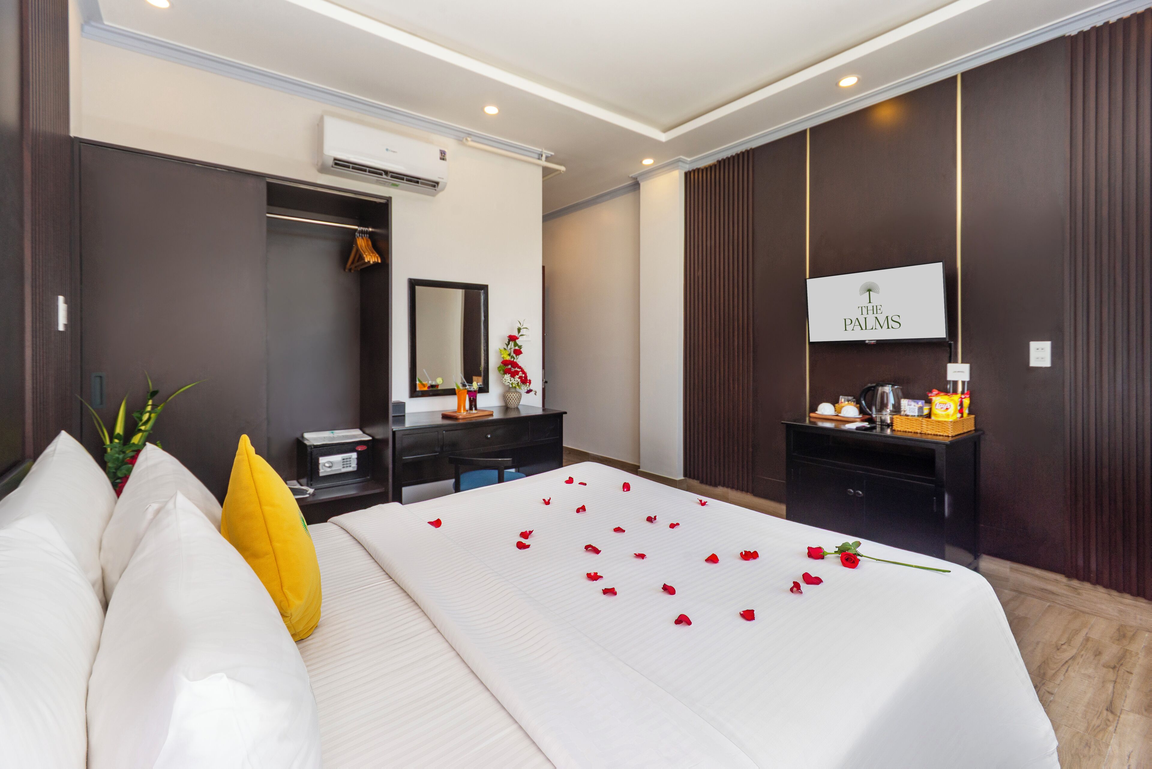 Quarto de hotel com cama grande, escrivaninha, espelho e televisão.