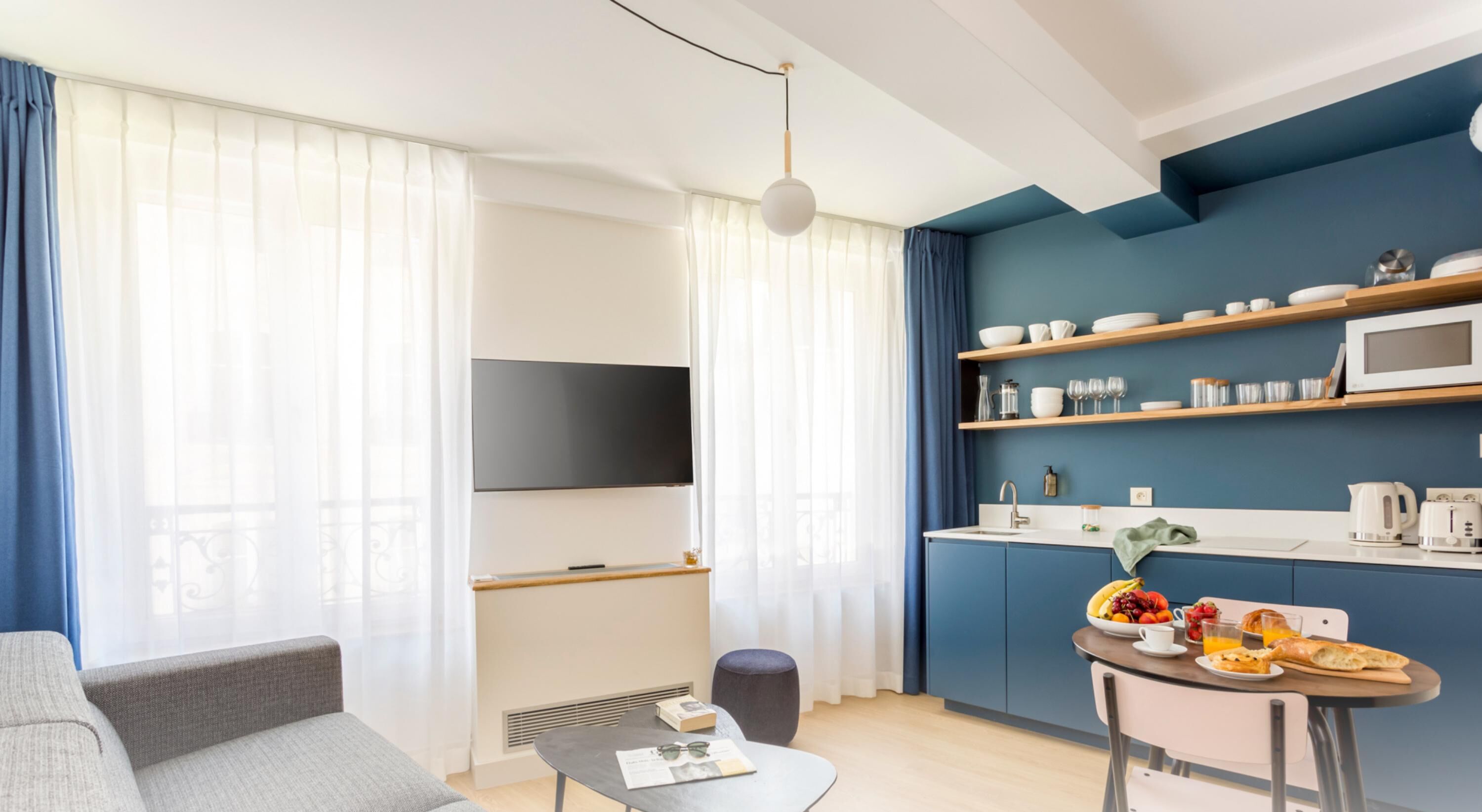 Uma sala de estar moderna com sofá, mesa de centro e área de jantar com mesa posta para o café da manhã.