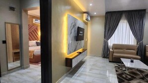 Uma sala de estar moderna com piso de mármore, televisão na parede, sofá e mesa de centro.