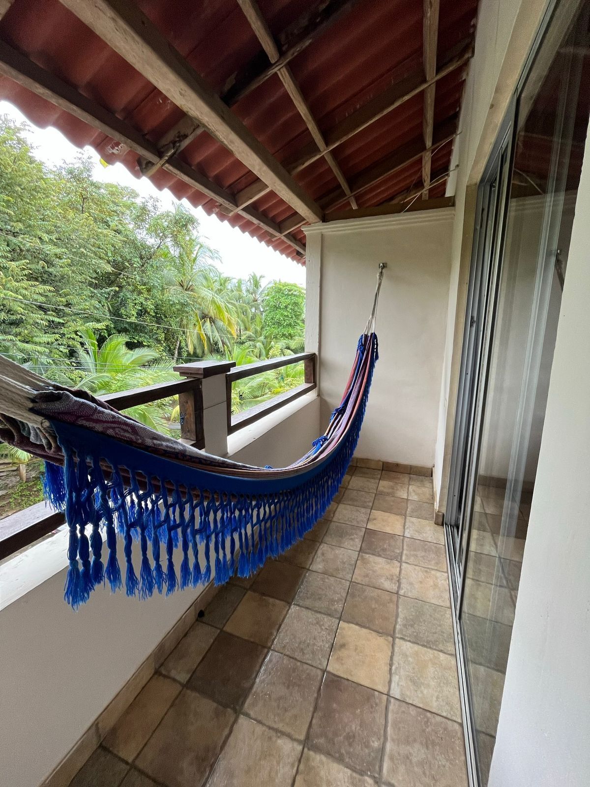 Uma rede numa varanda com vista para o verde.