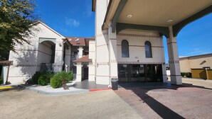 Um edifício com entrada coberta, fachada de tijolos e céu claro.