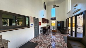 Um corredor com área de refeições, máquina de vendas automática e espaço de estar com ventilador de teto.