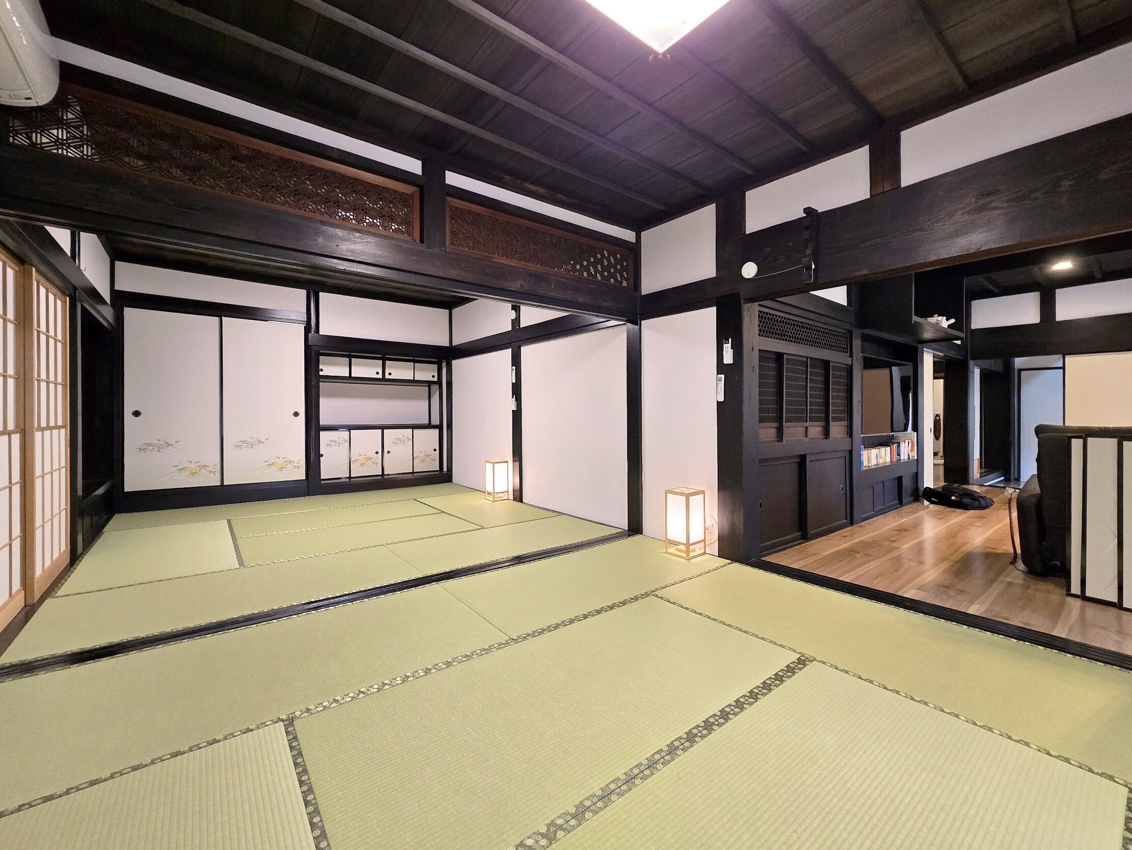 Um quarto japonês tradicional com tatame, portas deslizantes e teto de madeira.