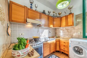 Uma cozinha com armários de madeira, fogão, pia e máquina de lavar.