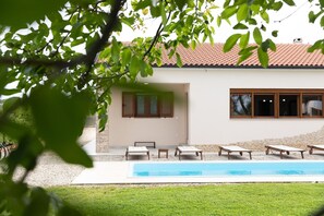 Um edifício com piscina, área de estar ao ar livre e telhado com telhas vermelhas.