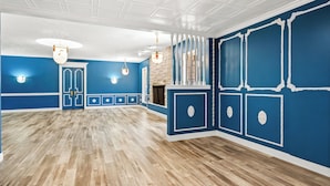 Quarto espaçoso com piso de madeira, paredes azuis, molduras brancas e uma lareira.