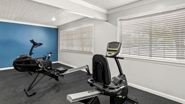 Uma academia com equipamentos de exercícios, uma parede azul e um teto com padrão decorativo.