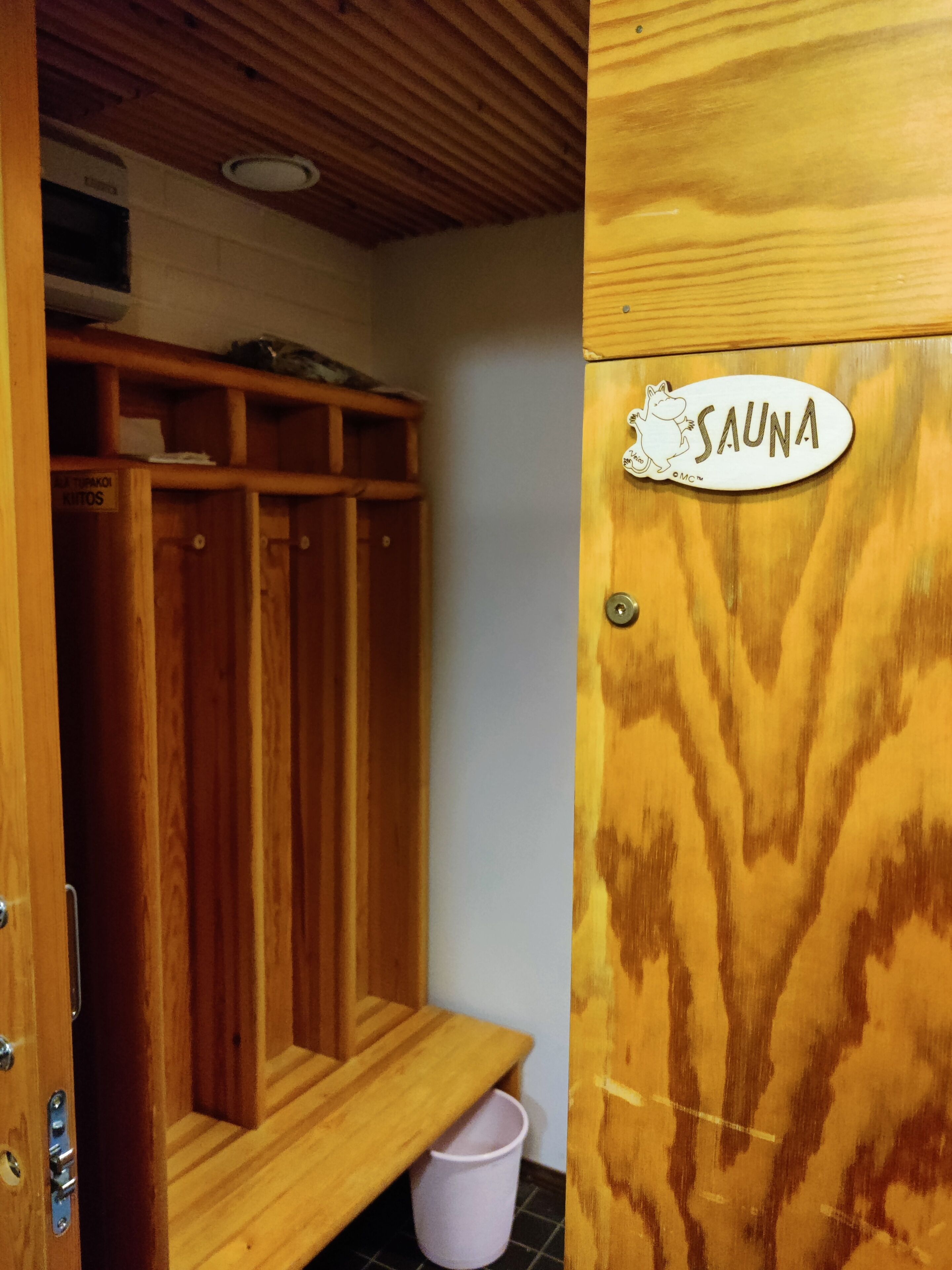 Uma sauna de madeira com um banco e um balde.
