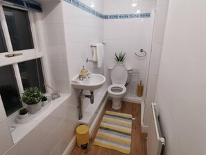 Casa de banho pequena com sanita, lavatório e janela.