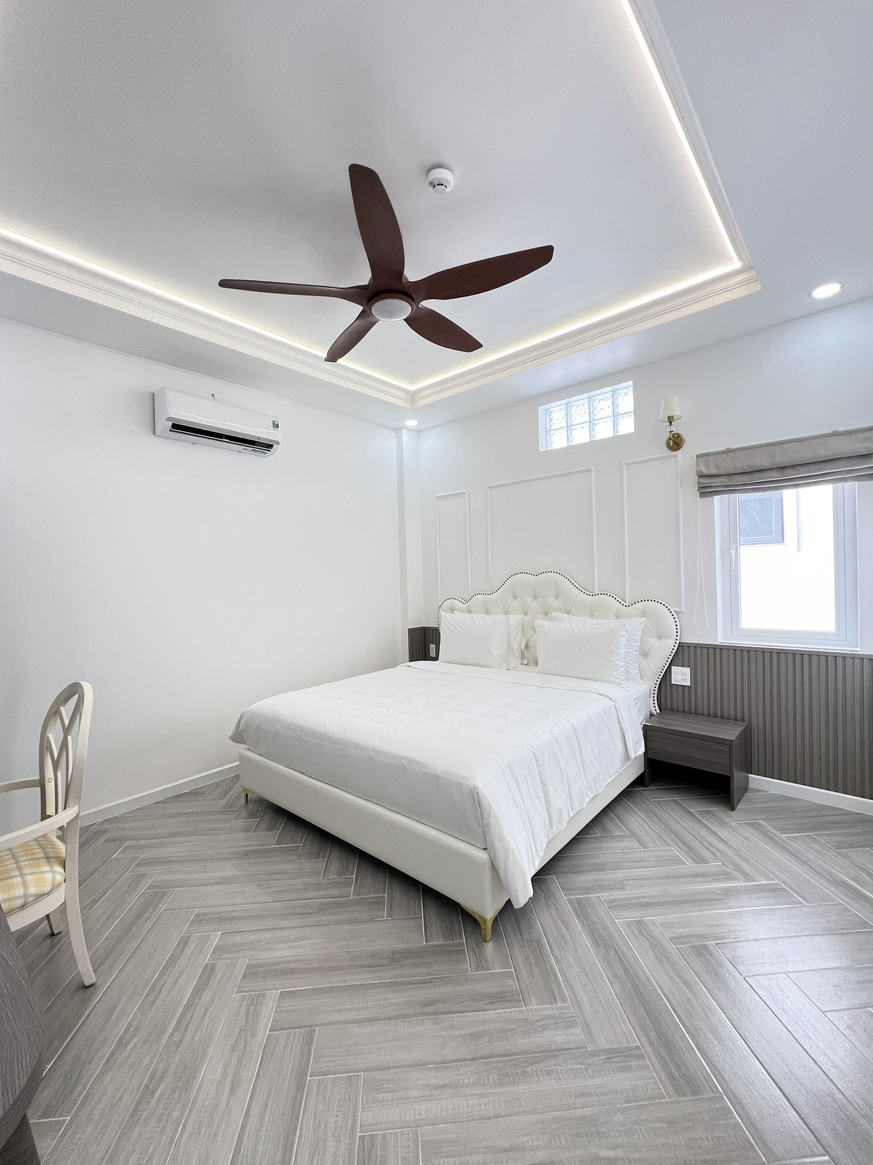 Quarto moderno com uma cama grande, um ventilador de teto, um ar condicionado e uma janela com vista.