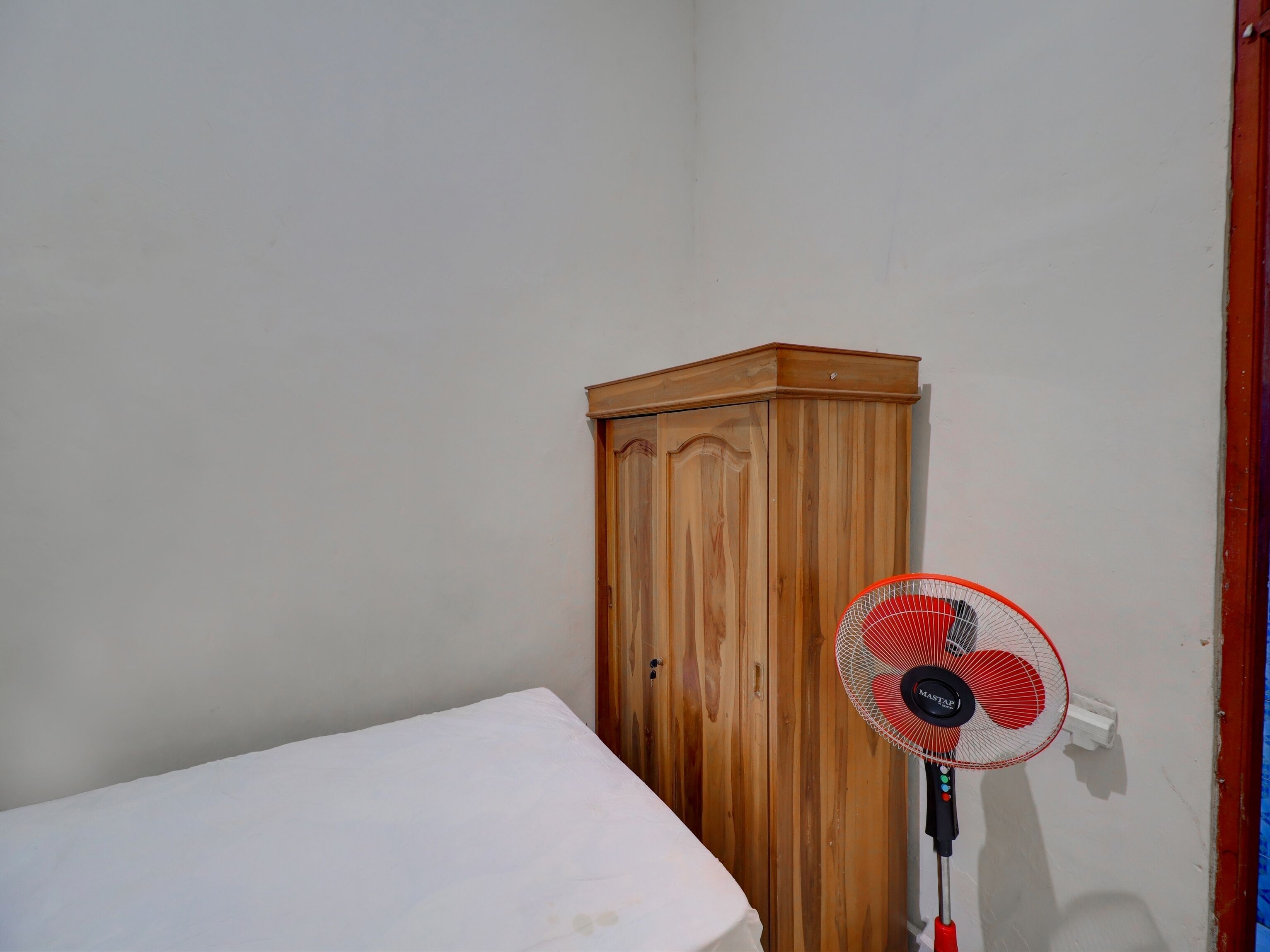 Quarto com guarda-roupa de madeira e um leque vermelho.