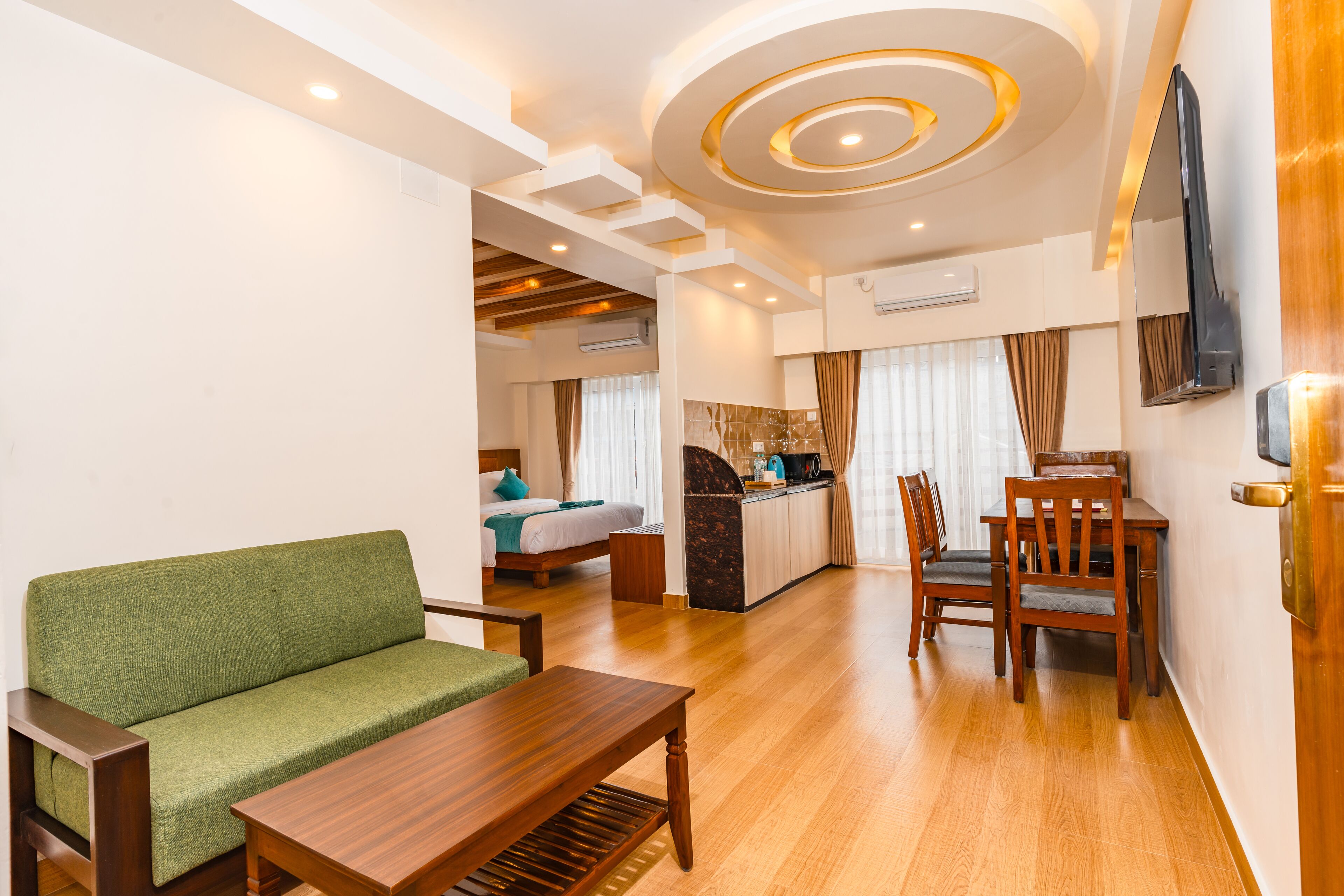 Uma sala de estar moderna com sofá, mesa de centro de madeira, área de jantar com cadeiras e cozinha ao fundo.