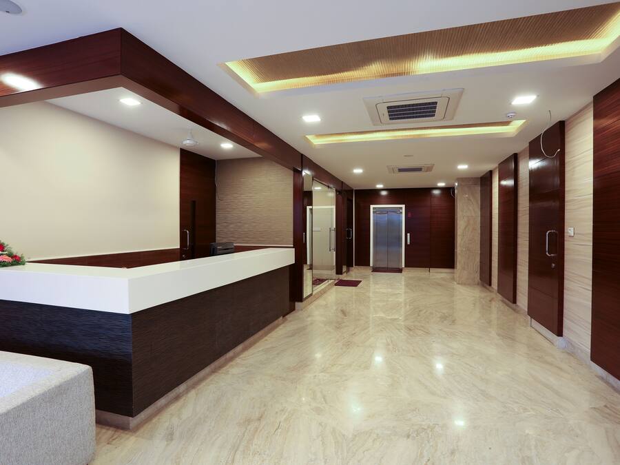 Uma área de recepção de hotel com piso de mármore, painéis de madeira e balcão de atendimento.