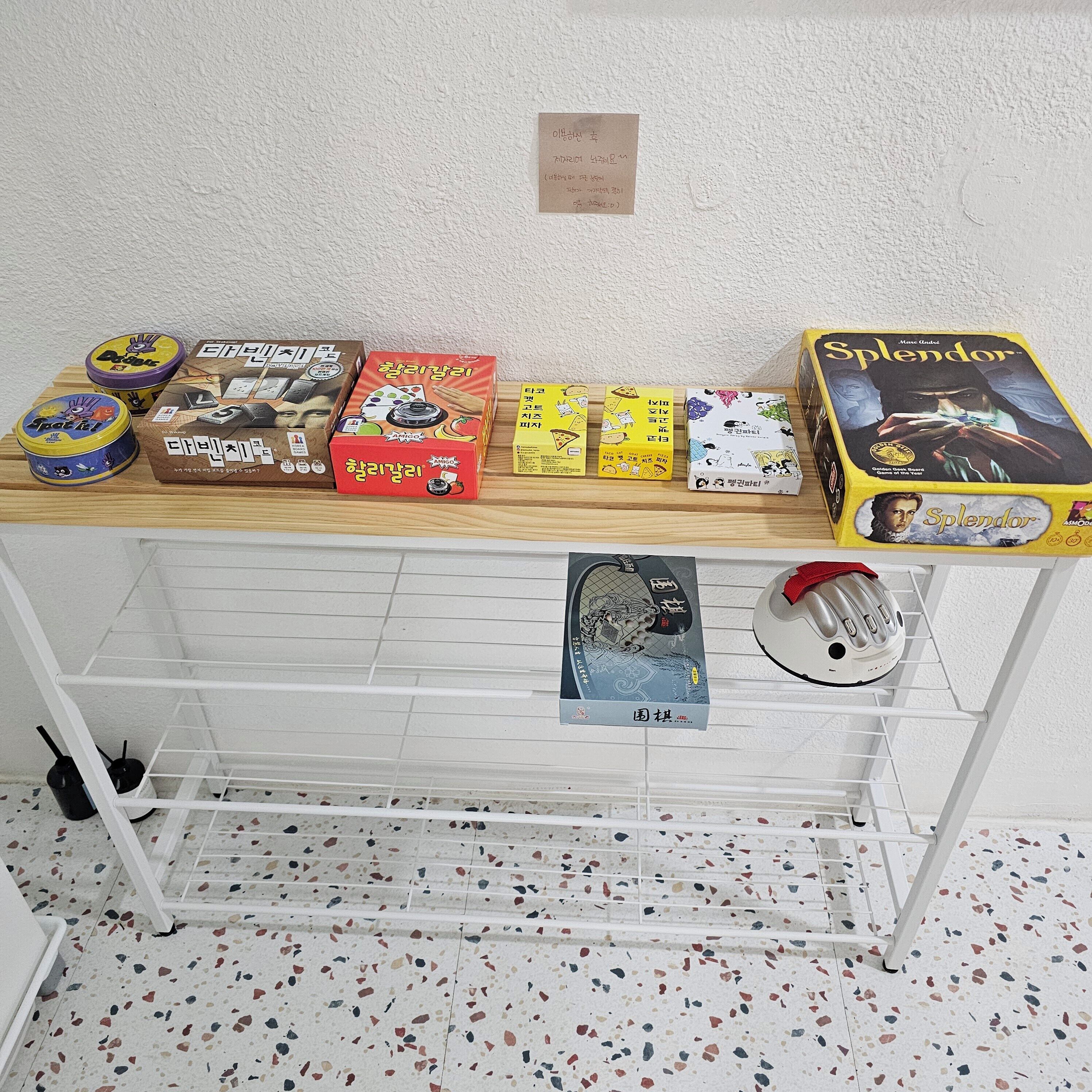 Uma mesa com jogos de tabuleiro e um capacete numa estante.